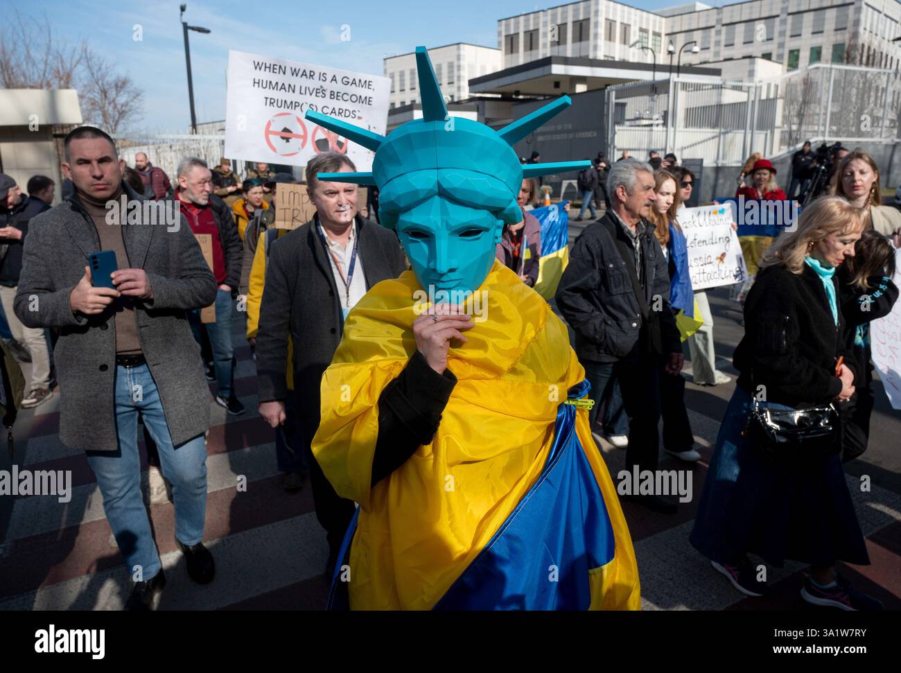 An activist wrapped in a Ukrainian flag wears a Statue of Liberty mask ...