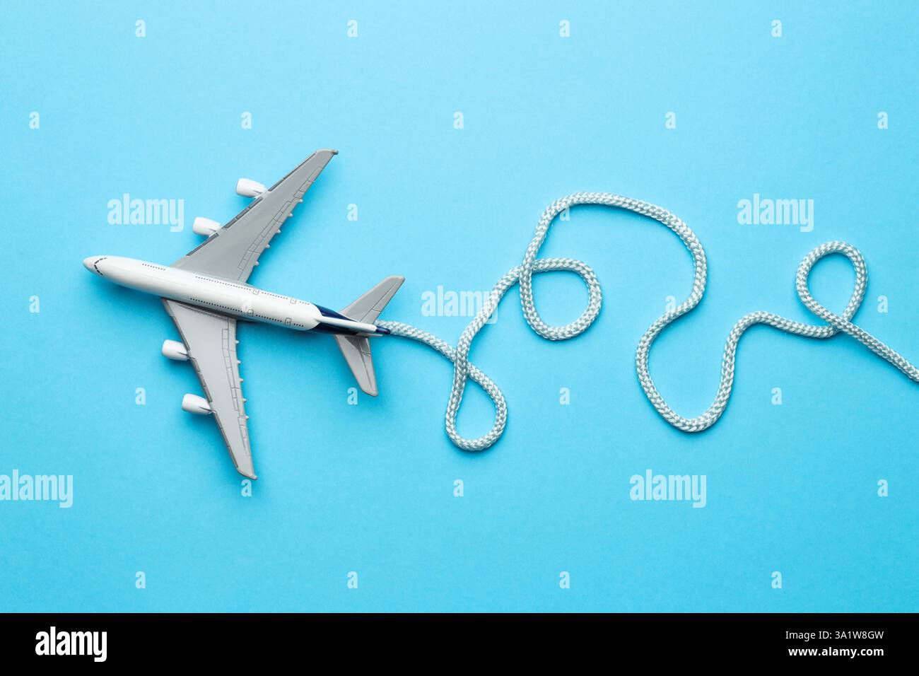 Plane model and rope as flight path on light blue background, top view ...
