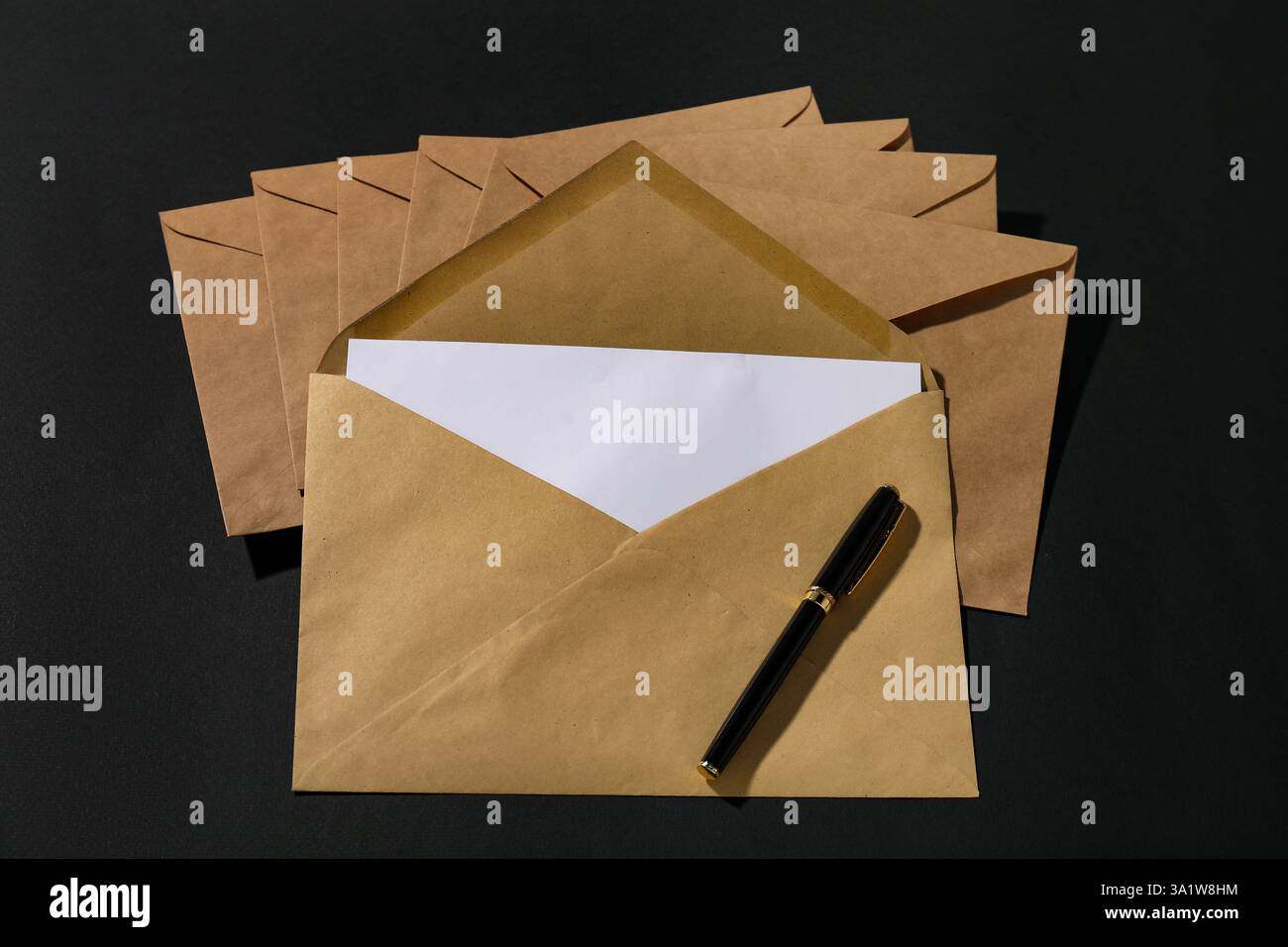 Kraft paper envelopes with letter and fountain pen on black background ...