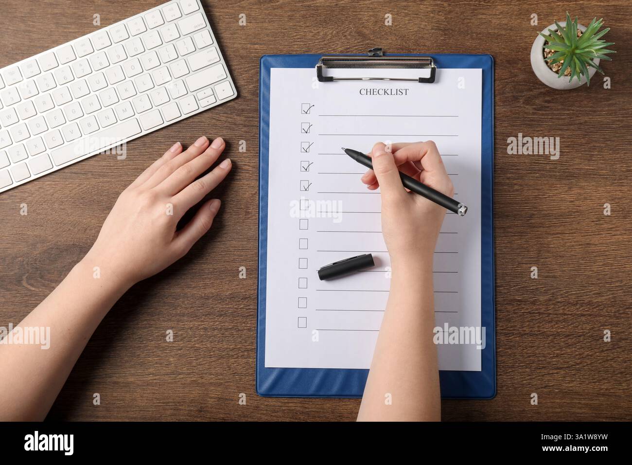 Woman filling Checklist at wooden table, top view Stock Photo - Alamy