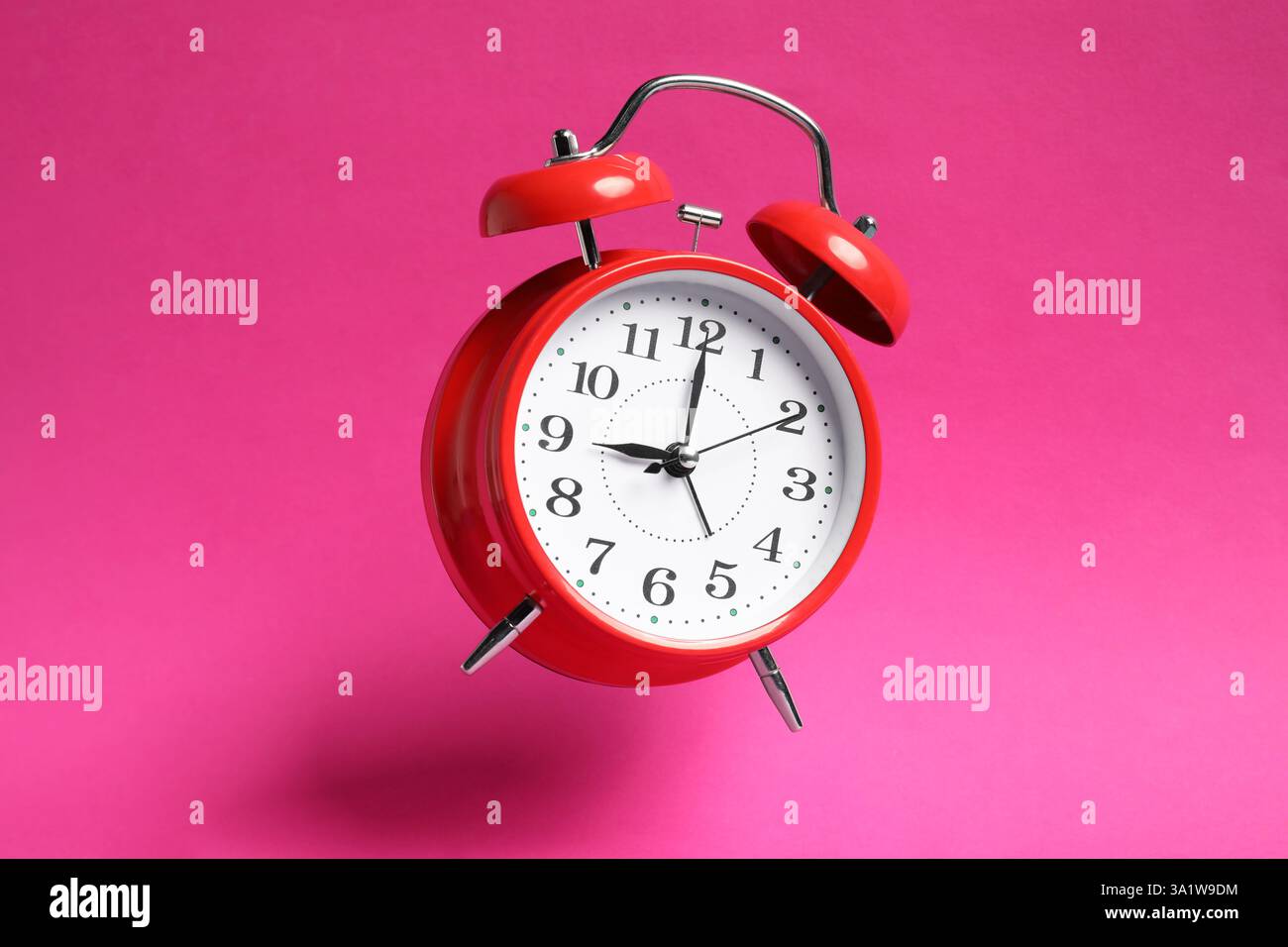 Red alarm clock in air on bright pink background Stock Photo - Alamy
