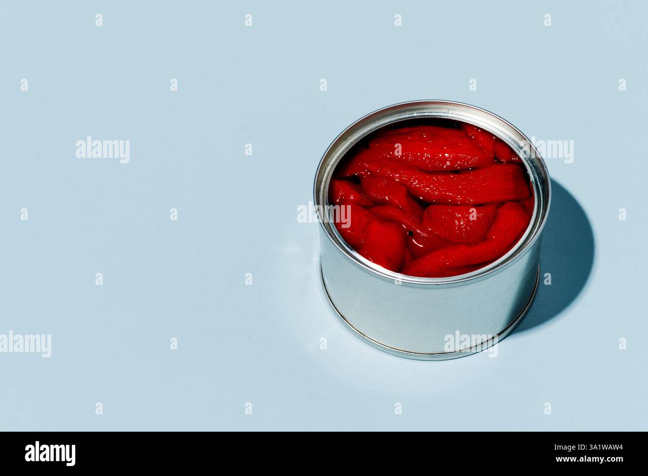 an open can of tinned roasted bell peppers placed on a light blue ...