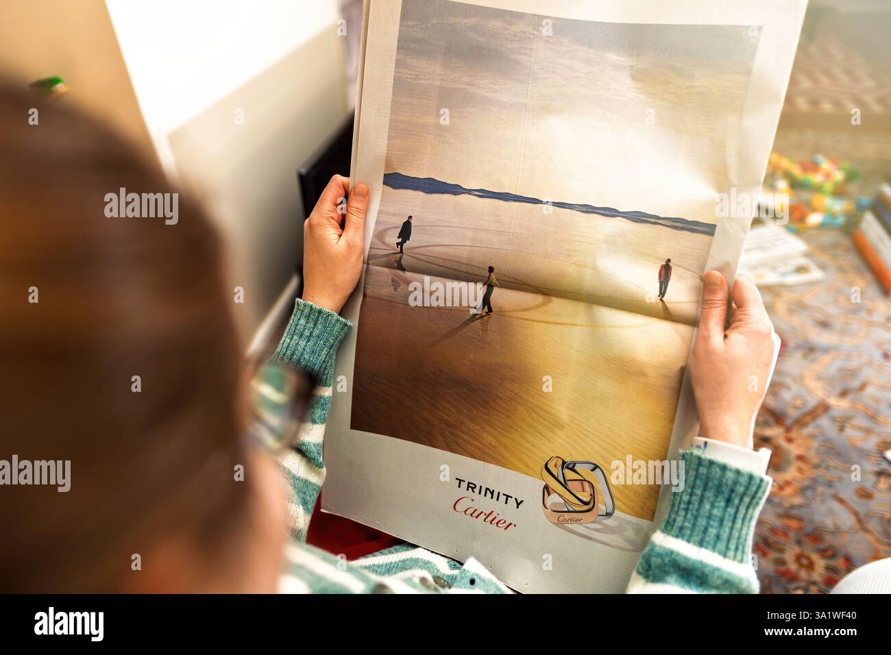 Paris, France - Dec 9, 2024: A woman holds up an e-newspaper displaying ...