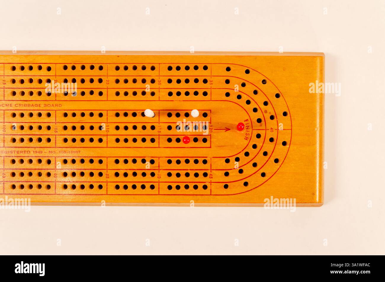 Overhead view of a cribbred and white age board with pegs finishing the ...