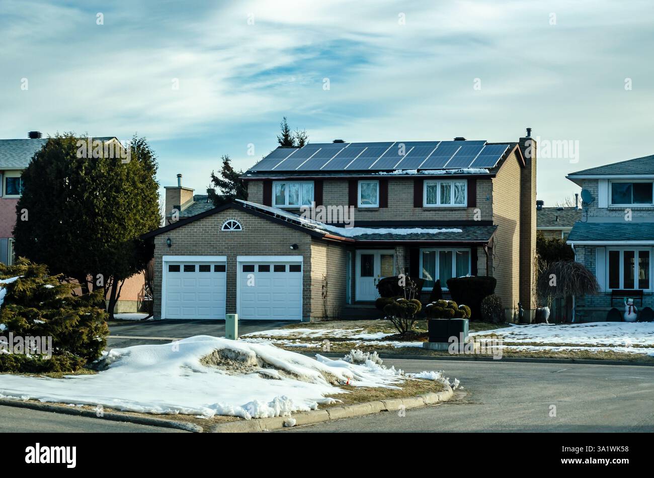 Solar panels on a brown brick suburban house rooftop and garage with ...
