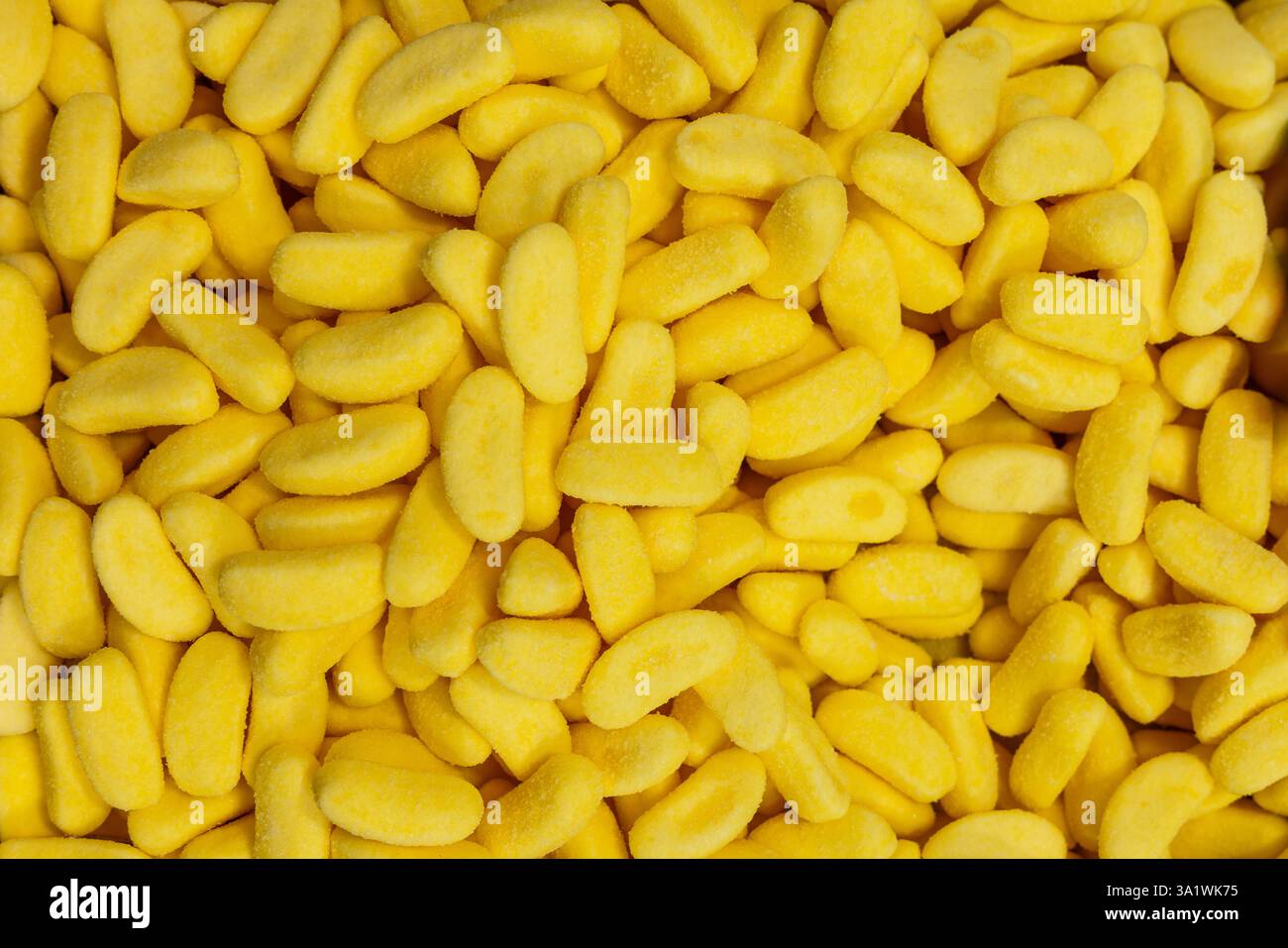 Background of yellow gelatin candies with a soft sugary coating and ...