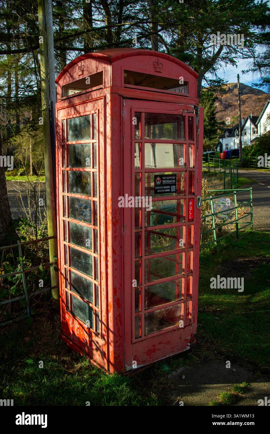 A tired and faded red, British telephone kiosk box repurposed to house ...