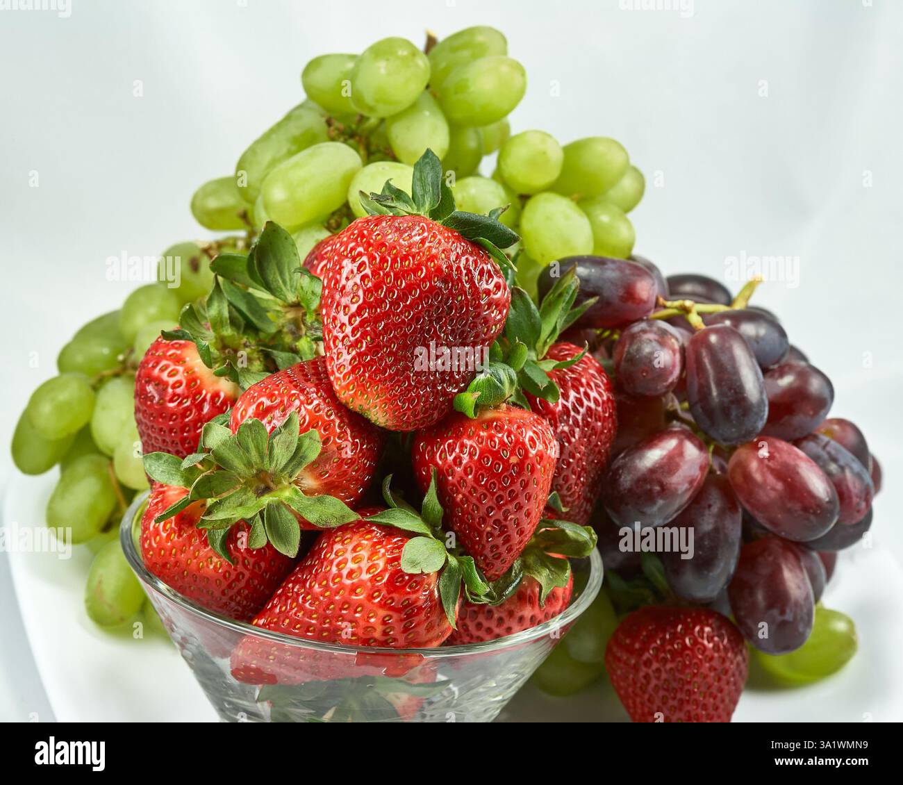 strawberries with grapes clustered on plate Stock Photo - Alamy