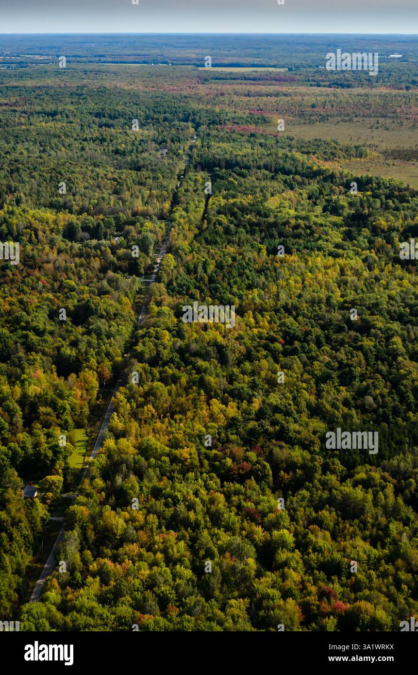Aerial view of early fall forest and farmland with an angled road ...