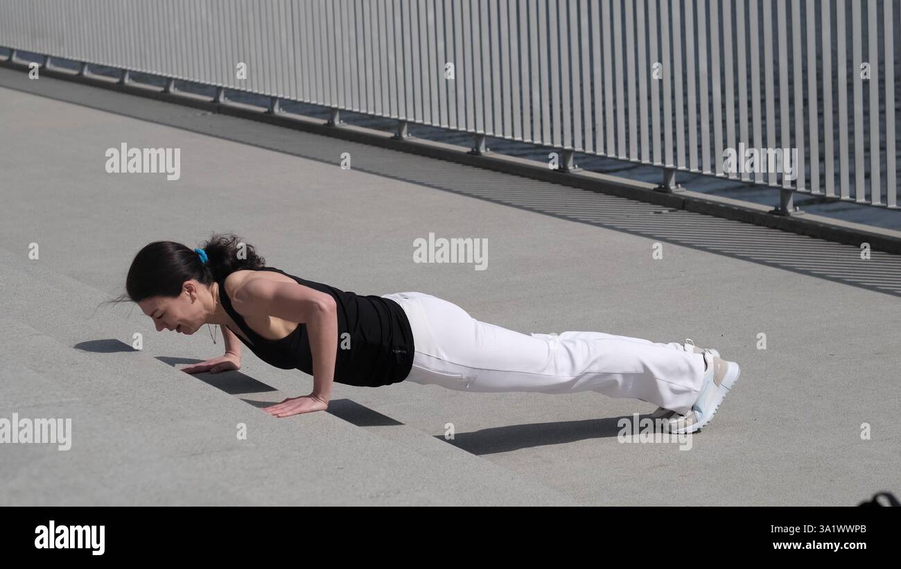 A fit woman engages in a bodyweight workout, executing a push-up with ...