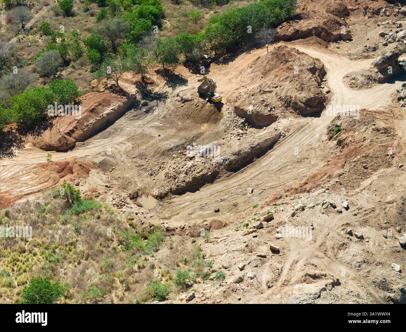 Heavy machinery operates in rugged area, reshaping land amidst dry soil ...