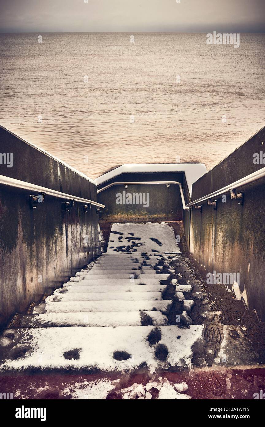 Footprints in the snow on steps leading down to the sea Stock Photo - Alamy