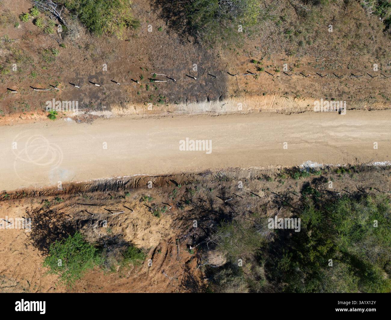 Dusty road stretches through mostly barren landscape, surrounded by ...