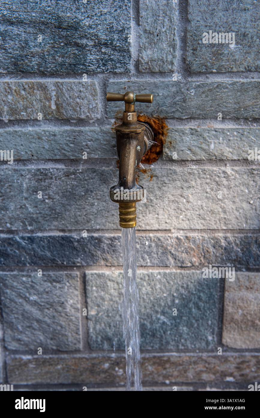 Outdoor tap with valve open allowing a full flow of water. The tap is ...