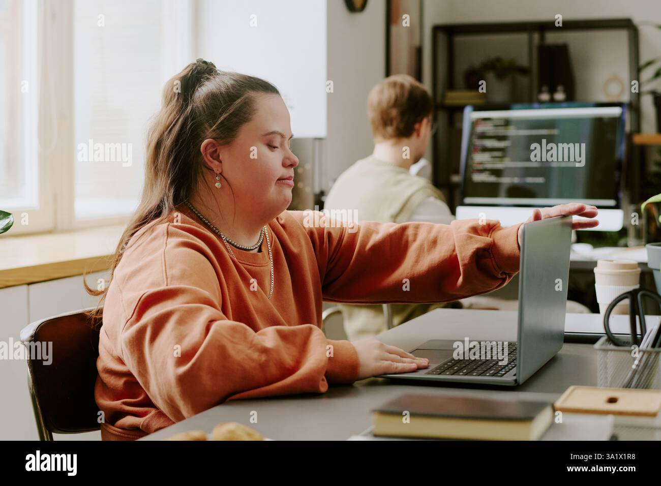 Medium shot of programmer with down syndrome opening laptop while ...