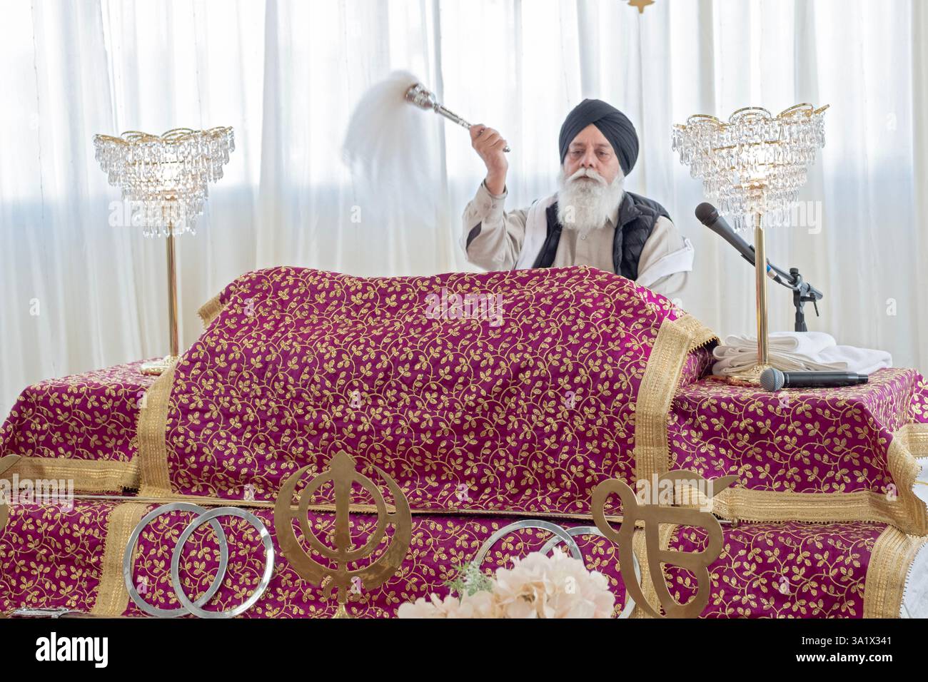 A priest waves a white Chaur Sahib over the Sikh holy book the Guru ...