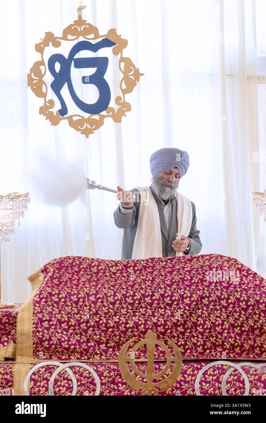 A priest waves a white Chaur Sahib over the Sikh holy book the Guru ...