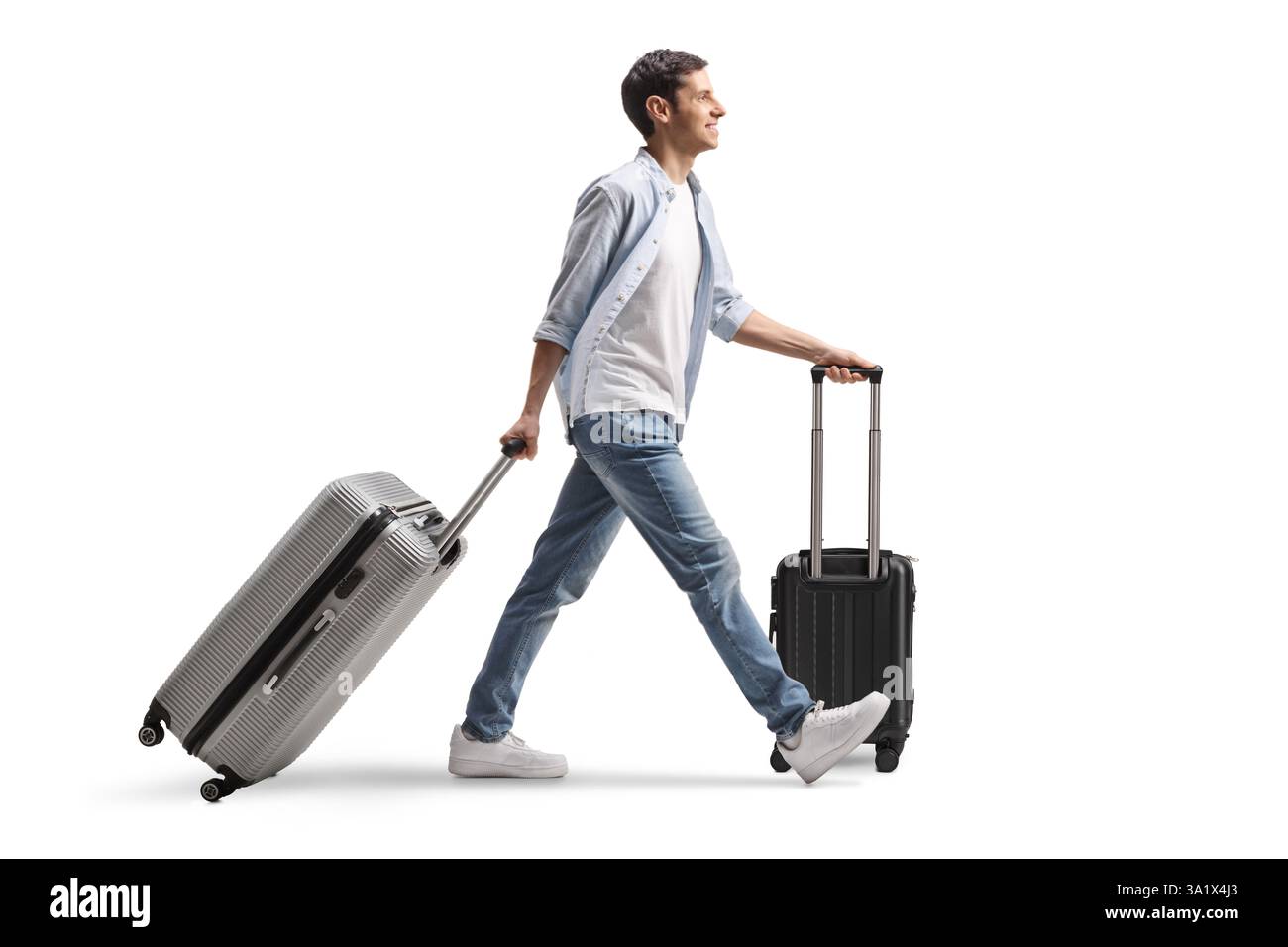 Full length profile shot of a casual young man pulling a suitcase ...
