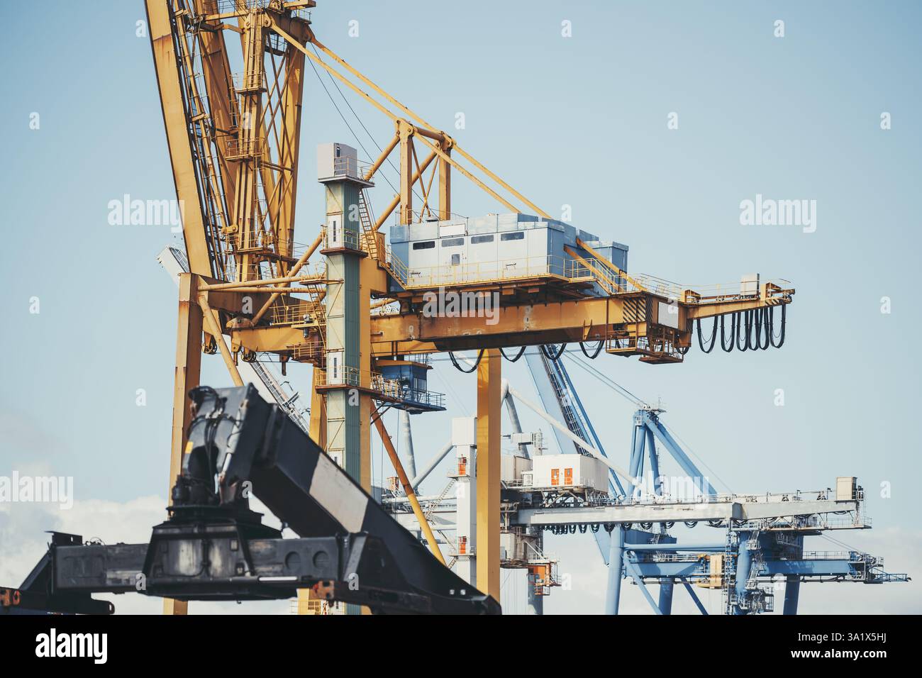 Telephoto shot of an industrial shipping port with large yellow and ...