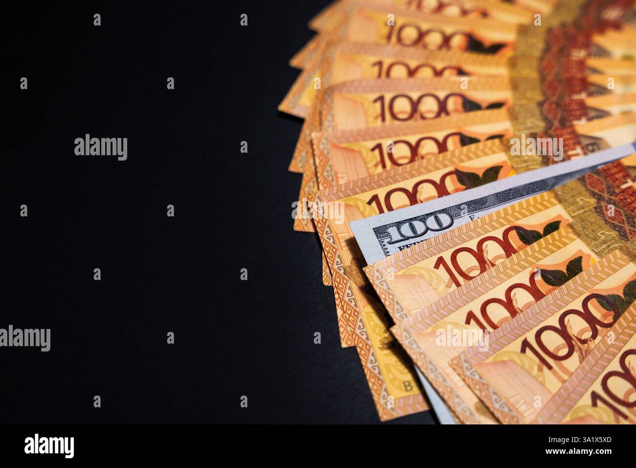 100 dollars among a fan of bills of 1000 tenge. Paper money from ...