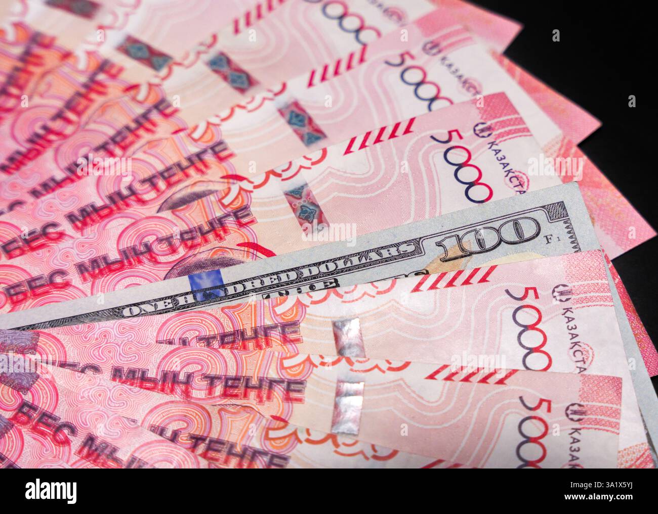 100 dollars among a fan of 5000 tenge bills. Paper money from ...
