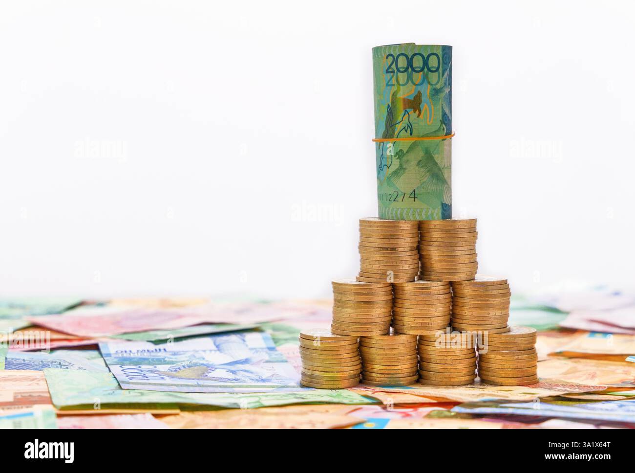 A folded 2000 tenge banknote stands on coins. Devaluation of money ...