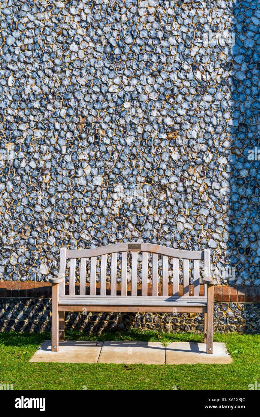 Vertical image of a wooden bench outside a traditional flint built ...