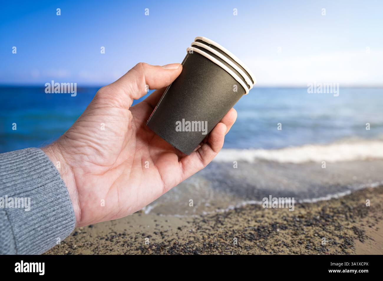 Hand holding disposable plastic cups on beach: pollution concept Stock ...