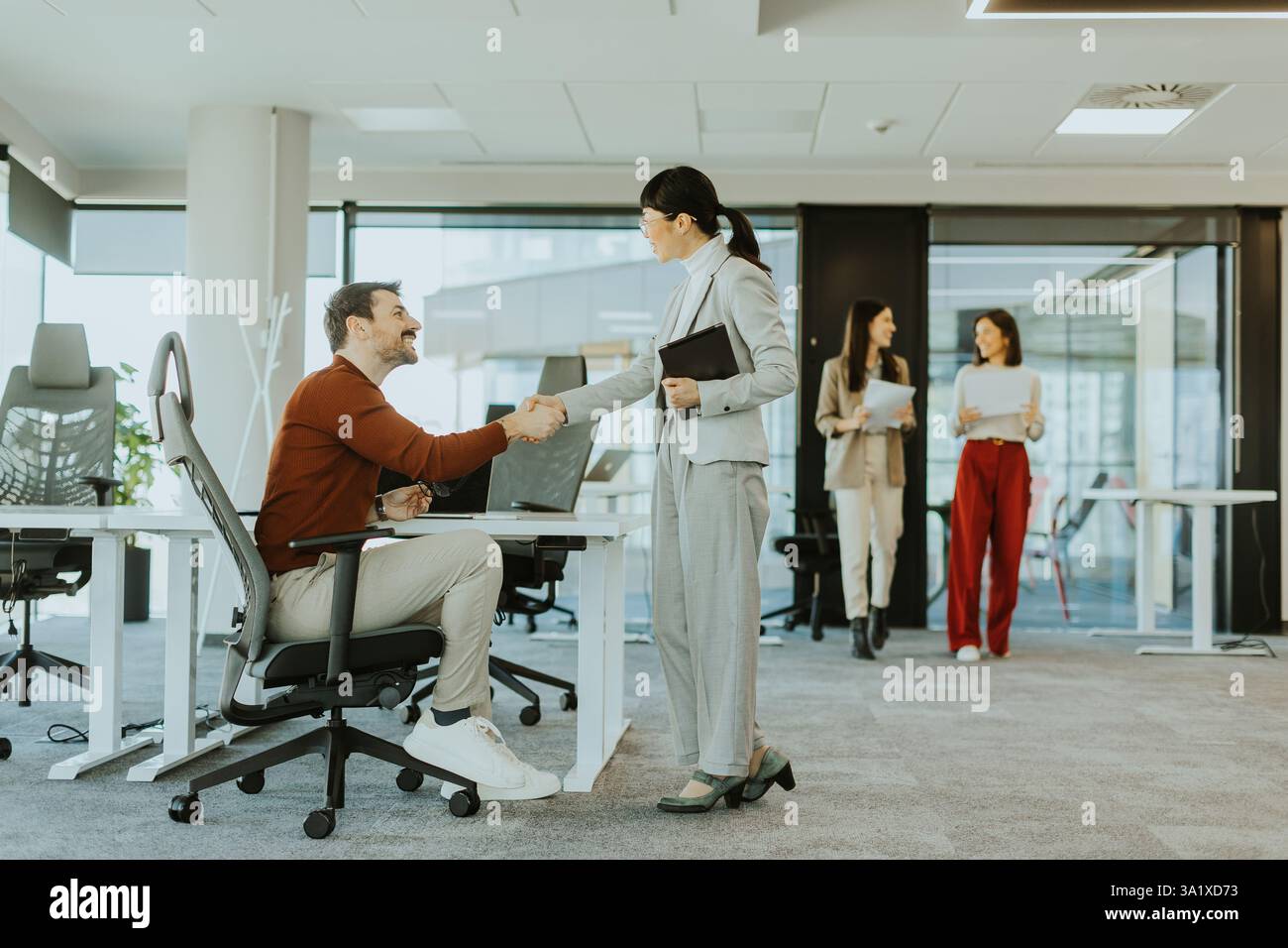 Two colleagues enjoy a moment of connection as they shake hands in a ...