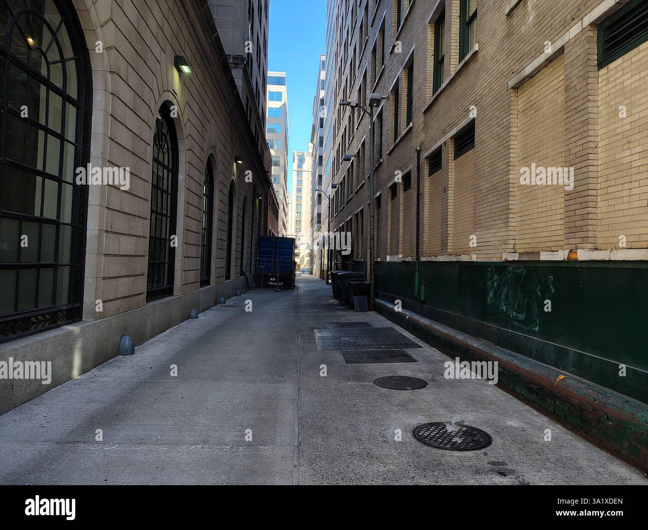 empty passage between dark brown buildings in downtown with exit to ...