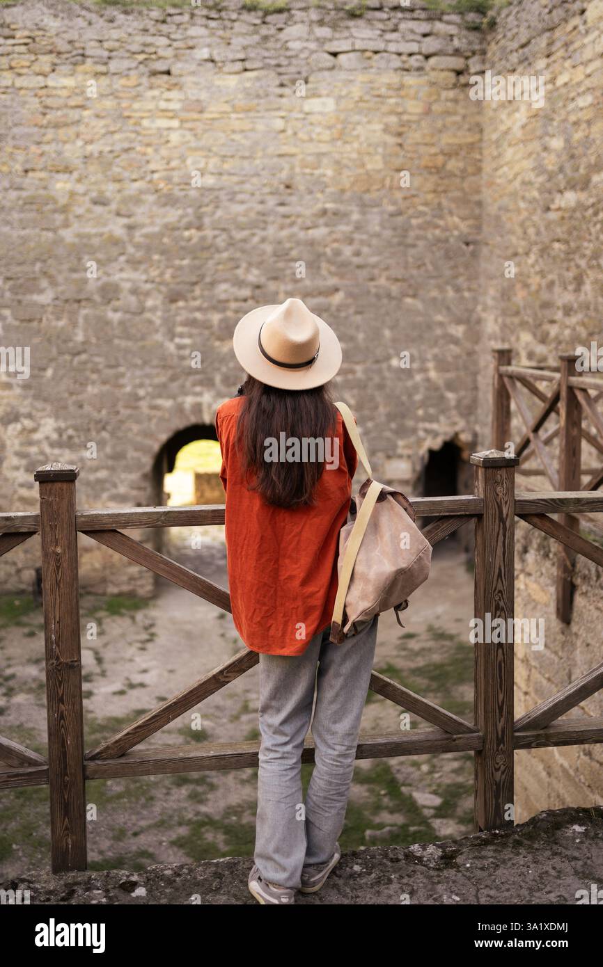Woman tourist with backpack and hat, looking at medieval UNESCO ...