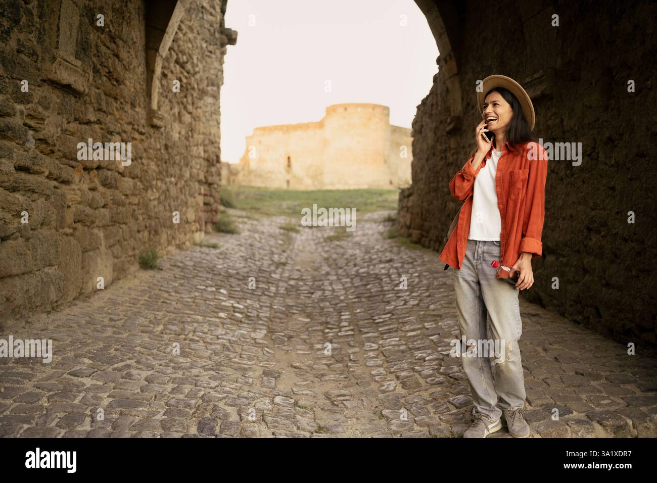 Tourist visiting medieval fortress standing near arch talking on cell ...