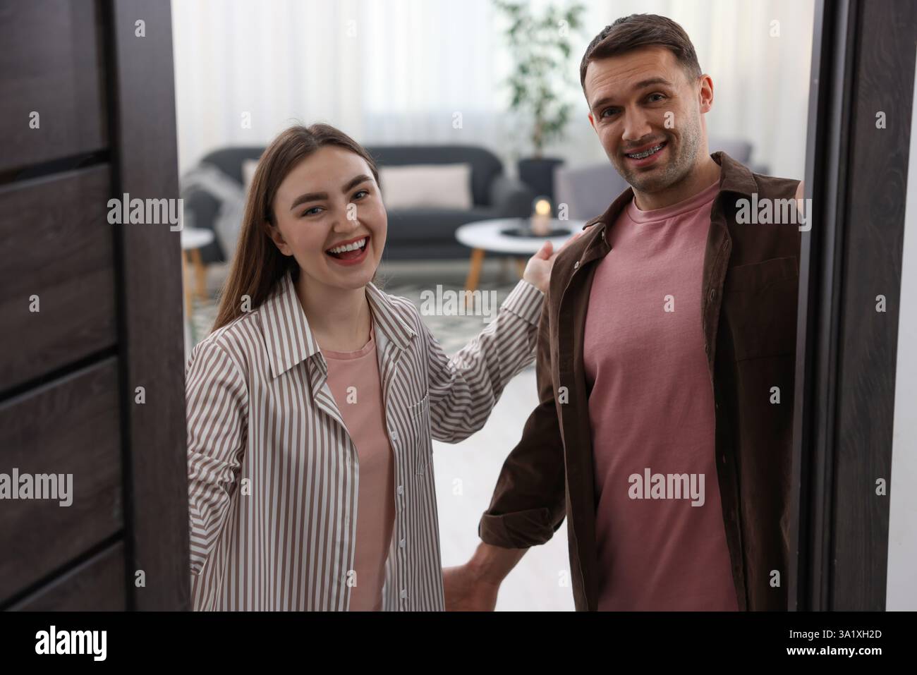 Lovely couple welcoming guests to their apartment Stock Photo - Alamy