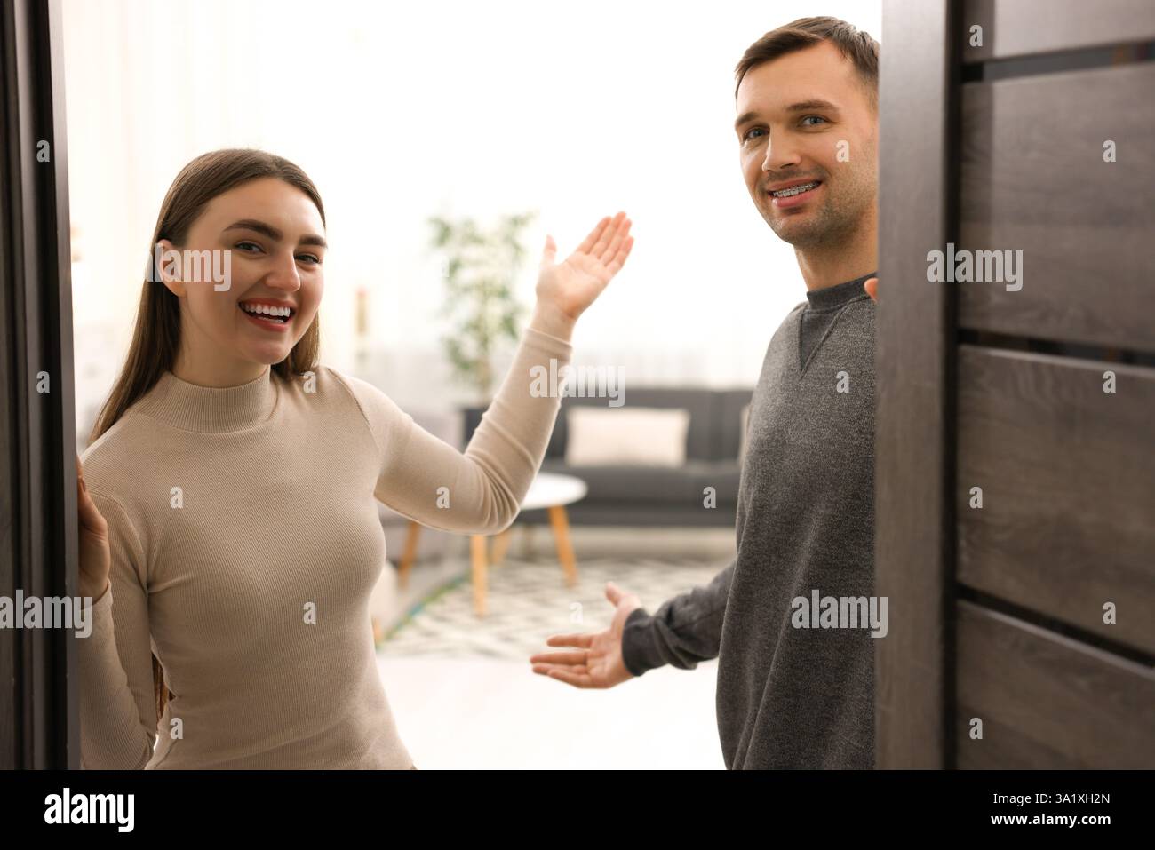 Happy couple welcoming guests to their apartment Stock Photo - Alamy