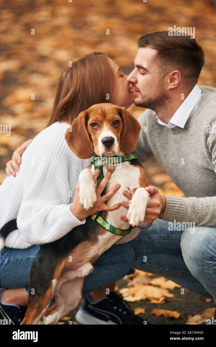 Kissing each other. Lovely couple are with their cute dog outdoors ...