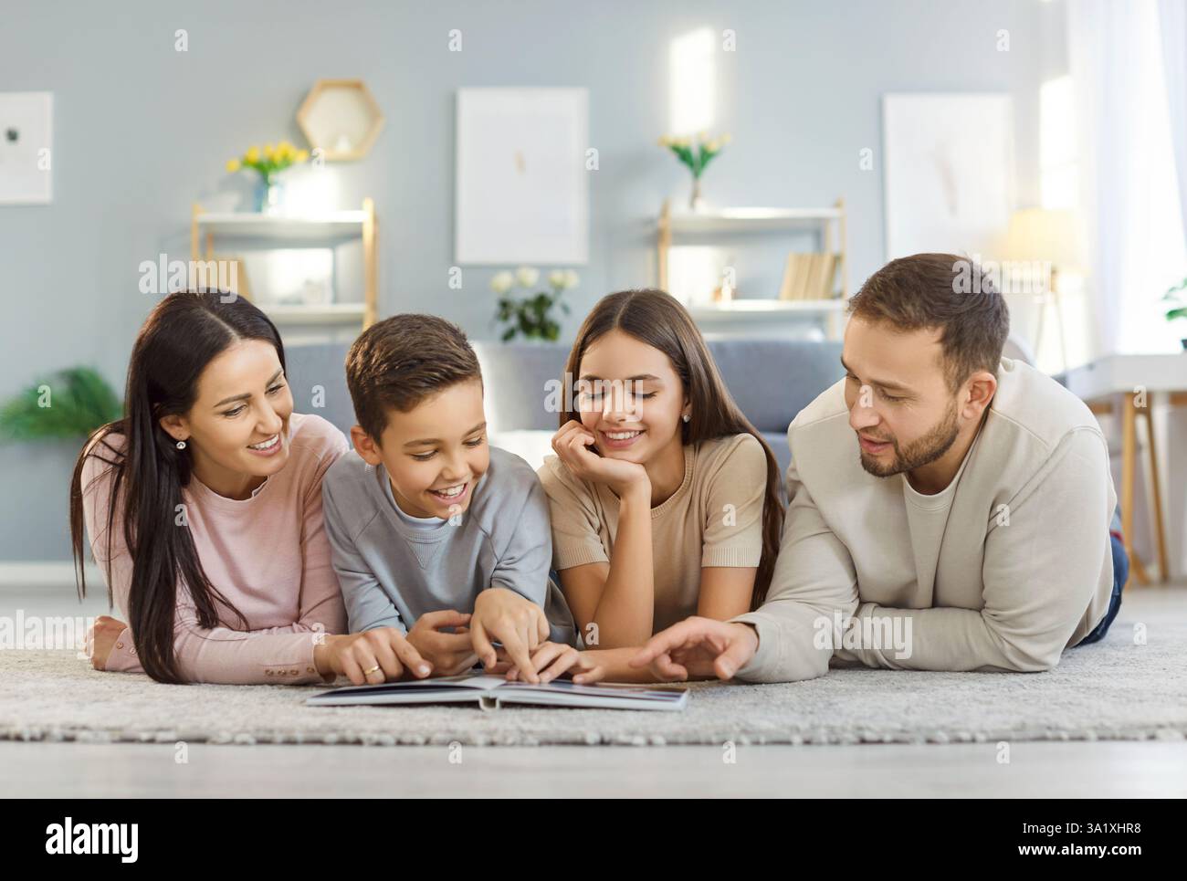 Happy family lying on carpet, looking through photo album, reminiscing ...