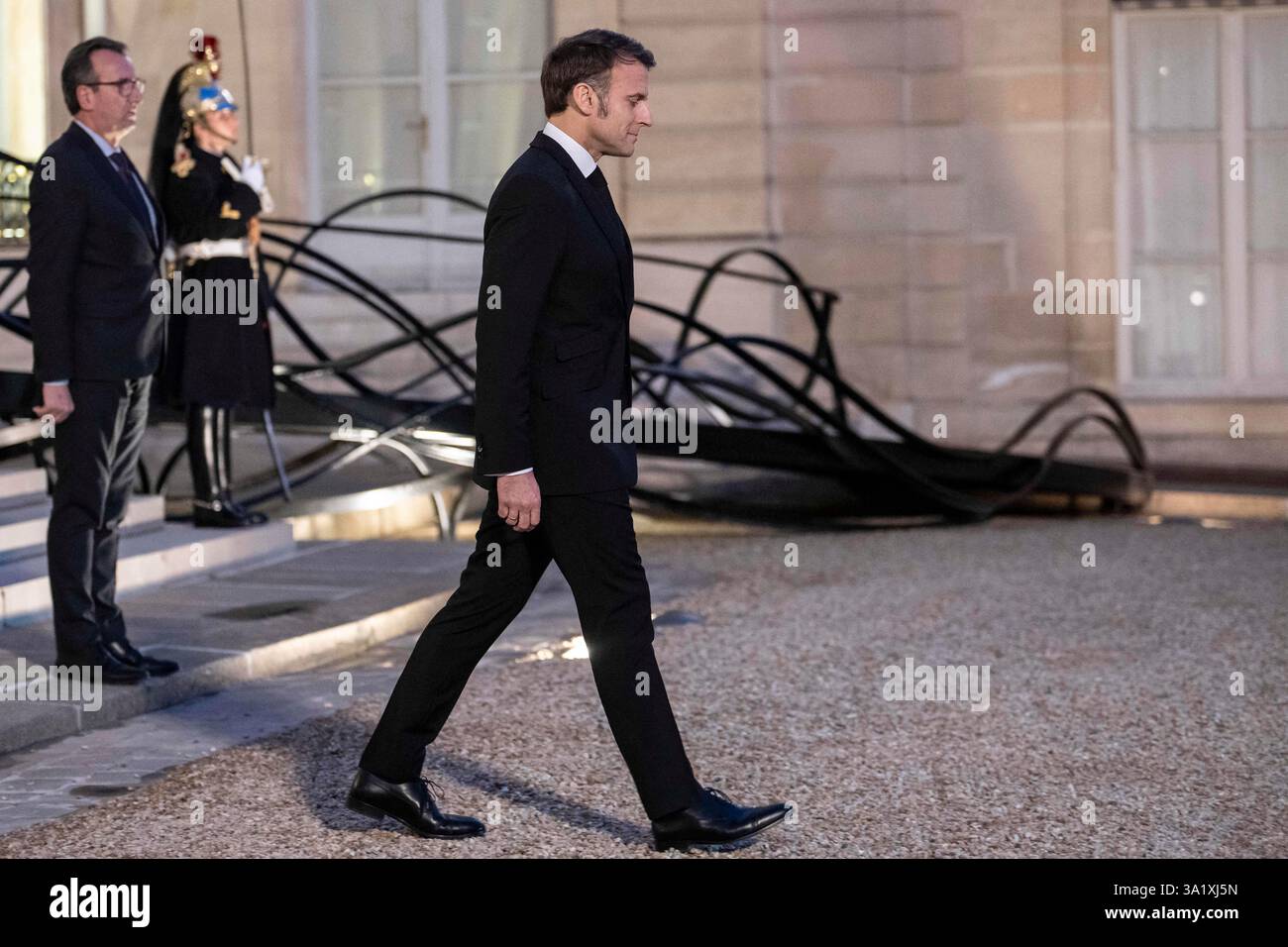 French President Emmanuel Macron walks alone at the Elysee palace in ...