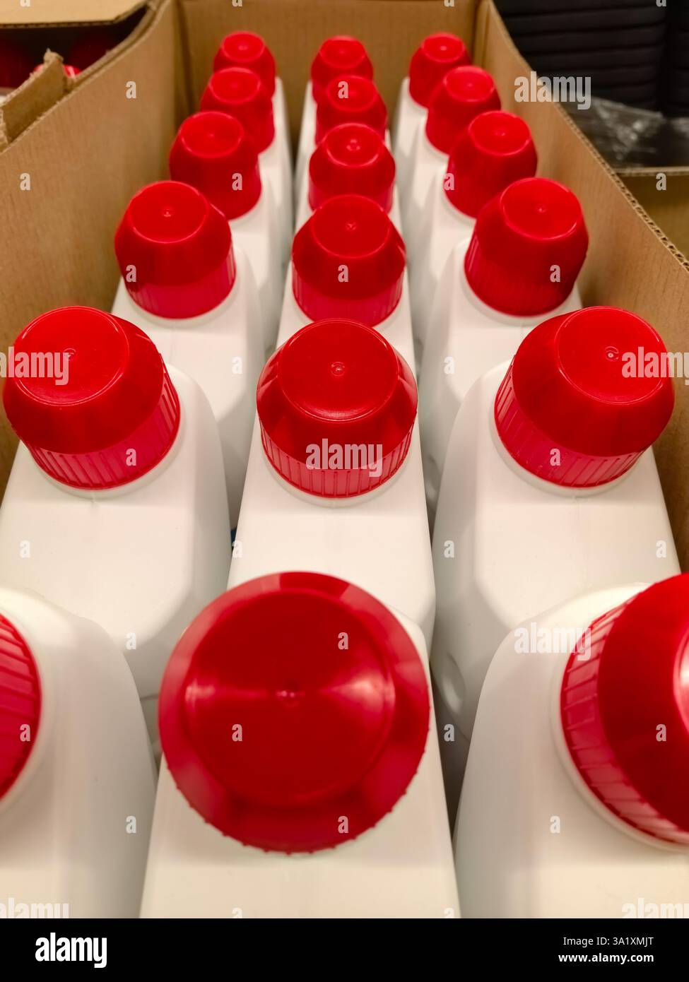 A collection of white bottles with bright red caps lined up inside a ...