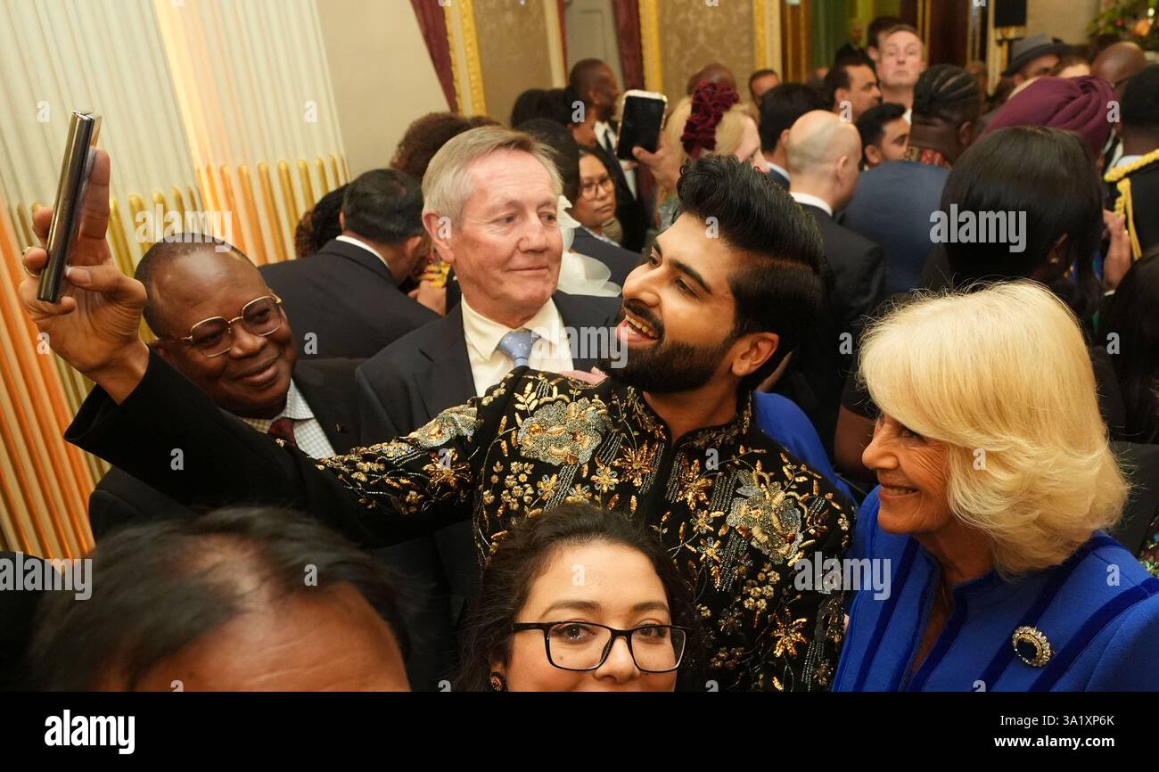 Queen Camilla (right) poses for a photo with a guest as he attends the ...
