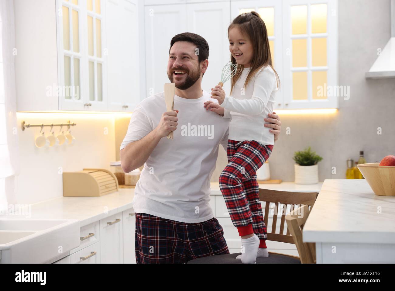 Father and his daughter wearing stylish pajamas having fun with ...
