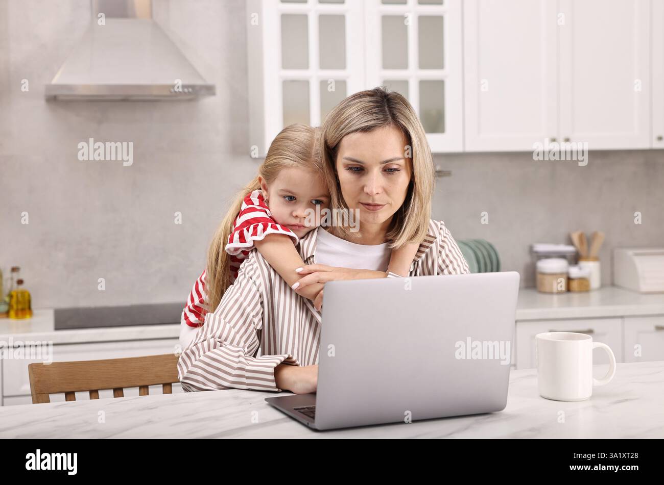 Work-family balance. Single mother working with laptop and her daughter ...