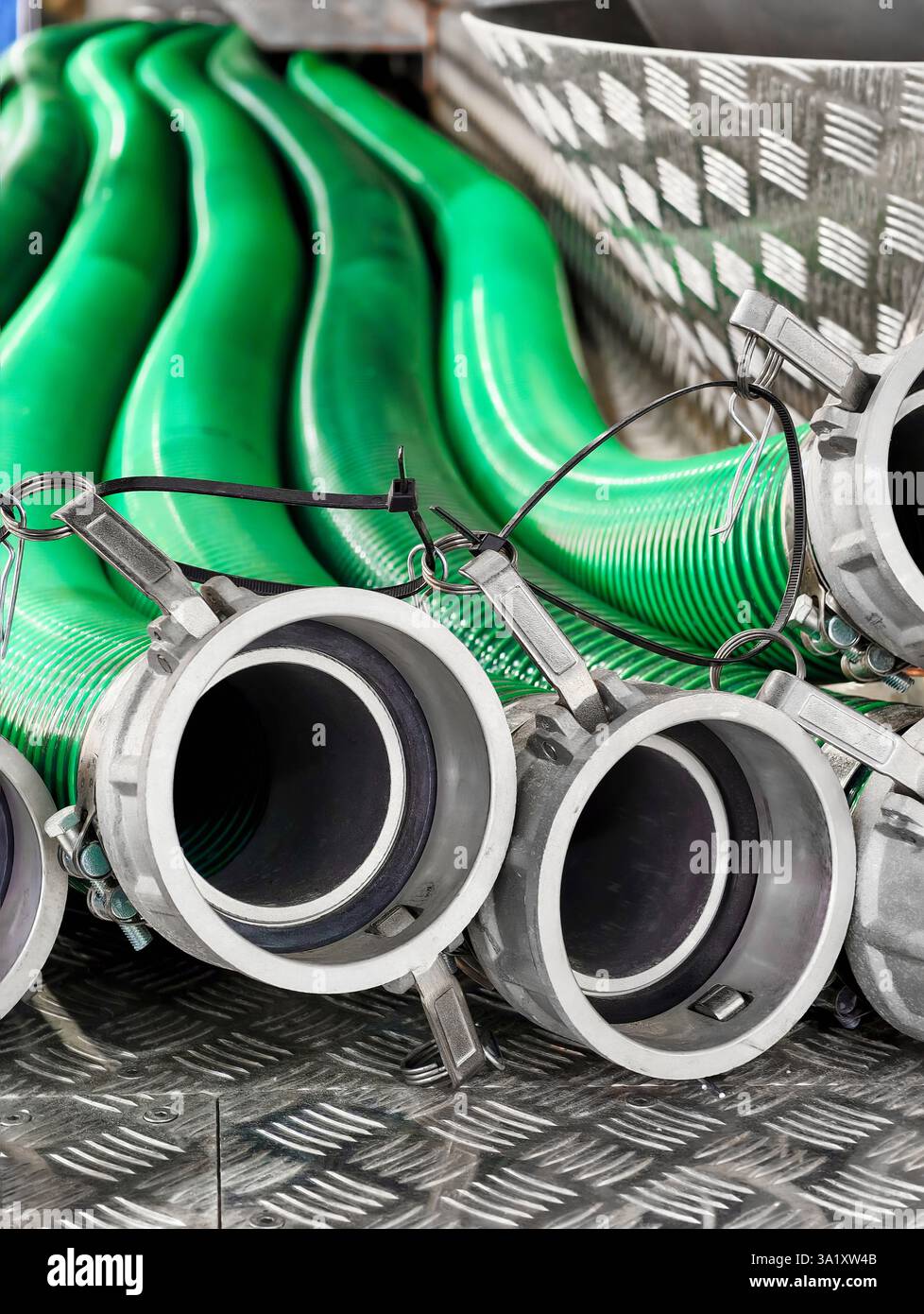 Green industrial hoses coiled and ready for use in a busy construction ...