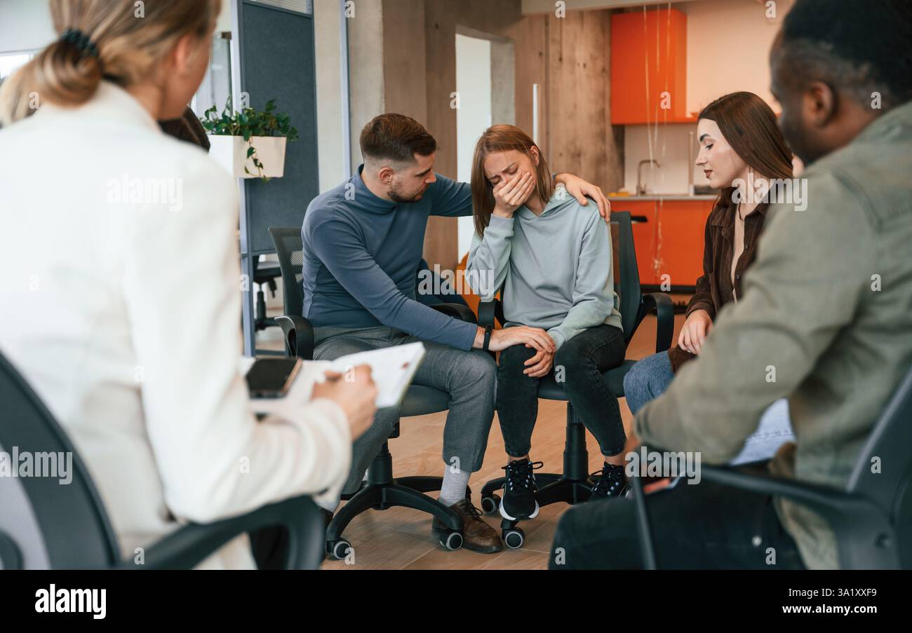 Woman is crying. Group of people are having therapy meeting together ...