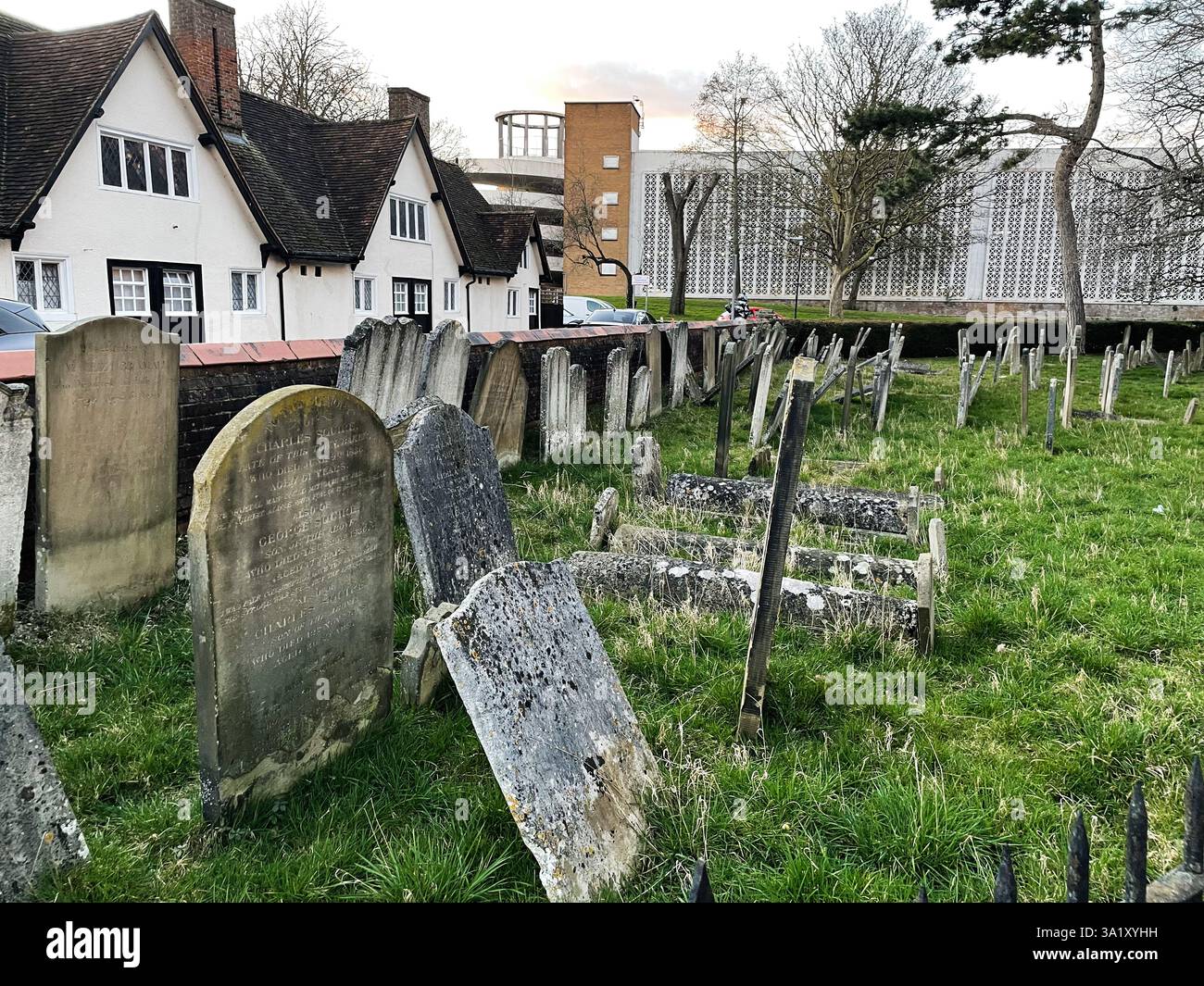 An old cemetery with gravestones beside cottages and modern buildings ...