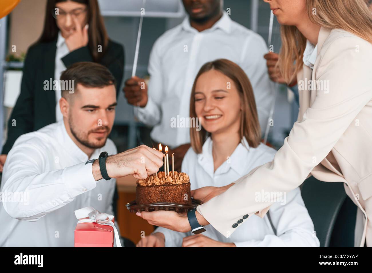 Igniting the candles on a cake. Employee having a birthday in the ...