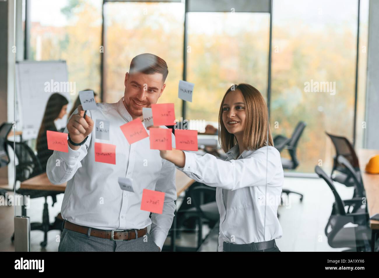 Two people are putting stickers on the glass. Planning the project ...