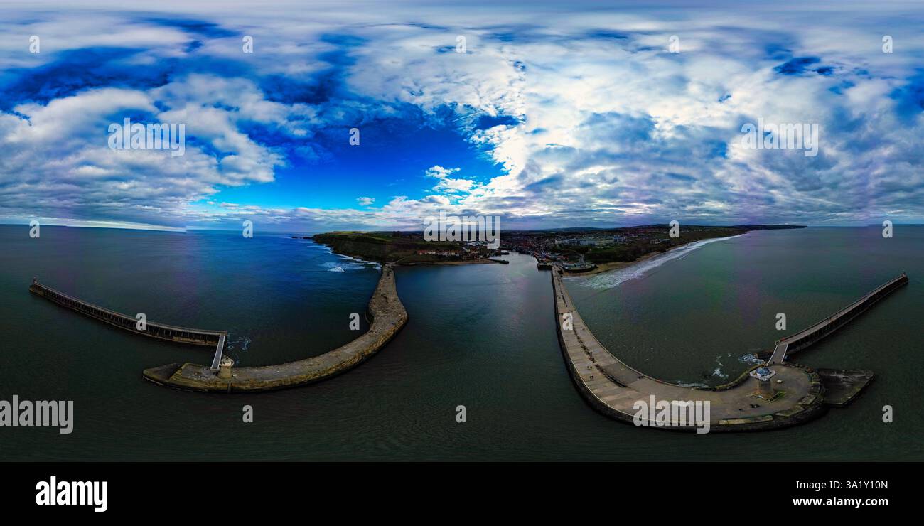 Panoramic view of a coastal town featuring two stone piers extending ...