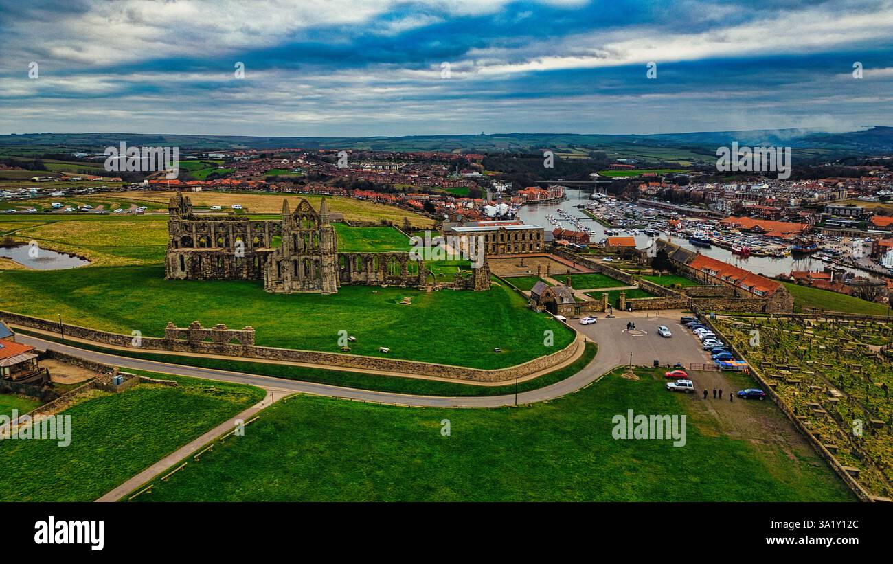Aerial view of Whitby Abbey ruins, a town with a harbor, green fields ...