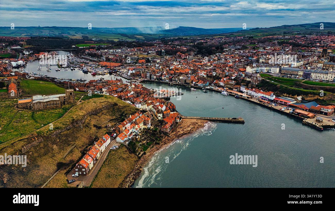 Aerial view of a coastal town bisected by a river, featuring red-roofed ...