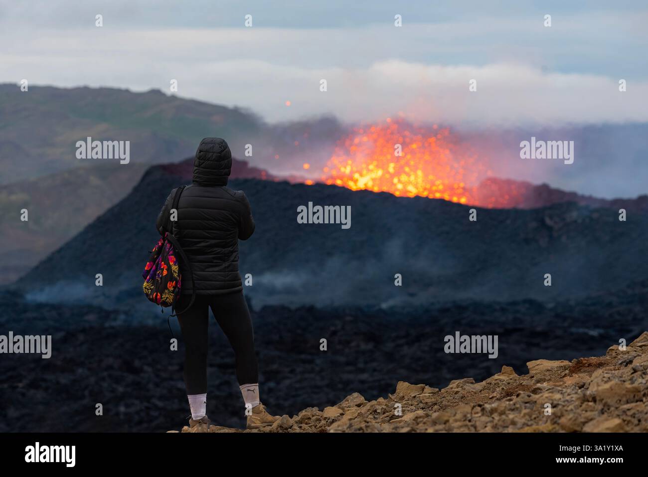 a woman are watching the power of nature of a volcano in iceland Stock ...